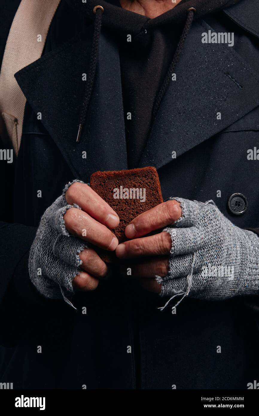 Man's hands holding piece of dark piece of bread, ragged gloves Stock ...