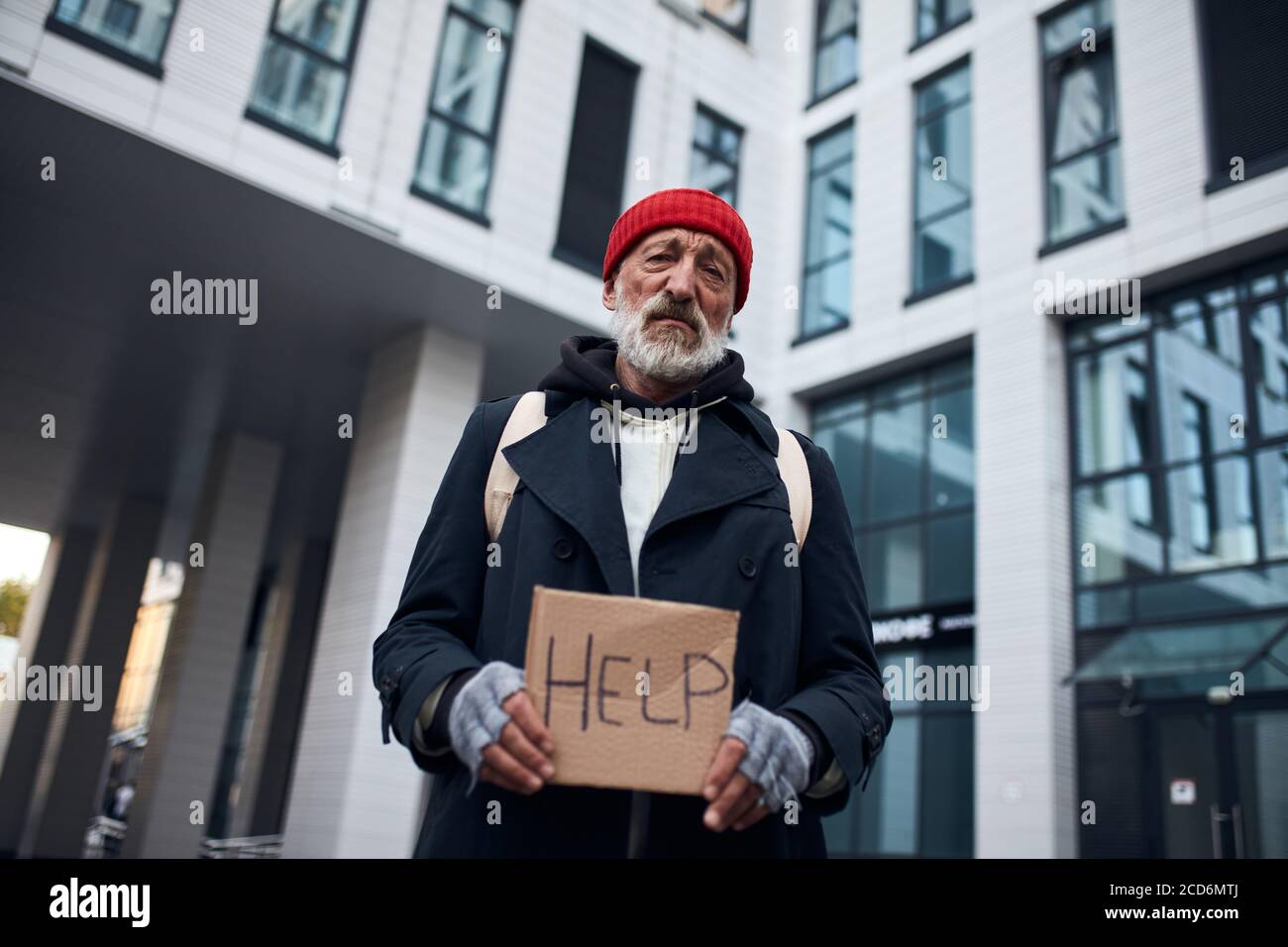Poor man holding help sign made by cardboard, stand in the center of ...