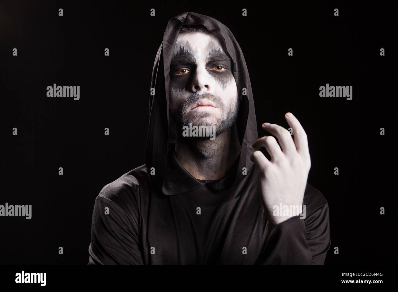 Spooky man dressed up like a grim reaper over black background ...
