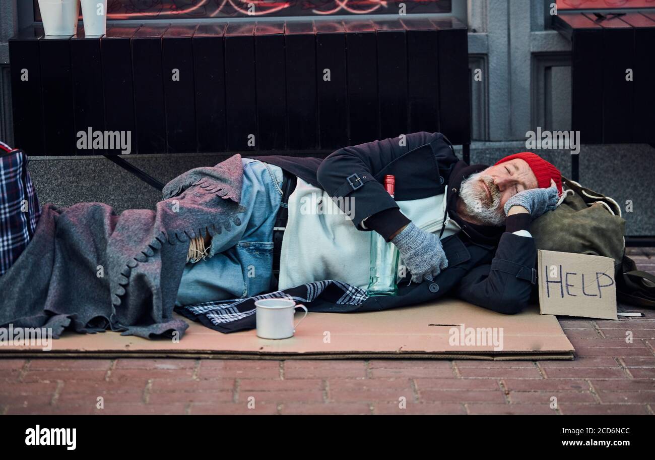 Homeless needy beggar male lying on cardboard box with sign HELP ...