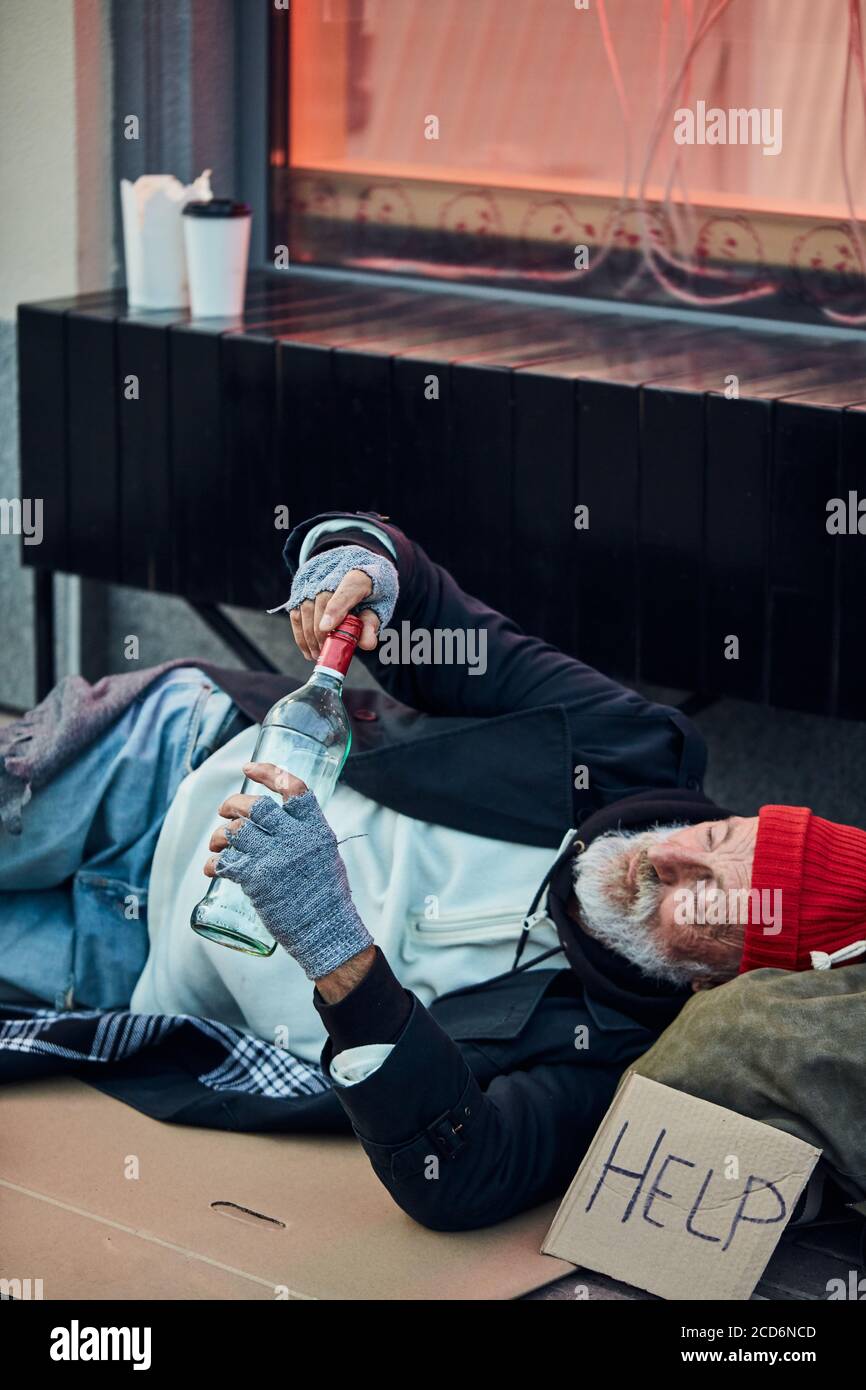 Homeless needy beggar male lying on cardboard box with sign HELP ...