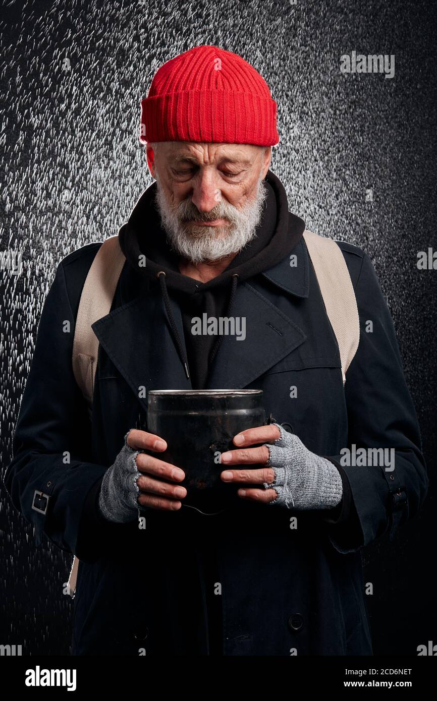 Bearded old man wearing black street clothes and holding iron cup for ...
