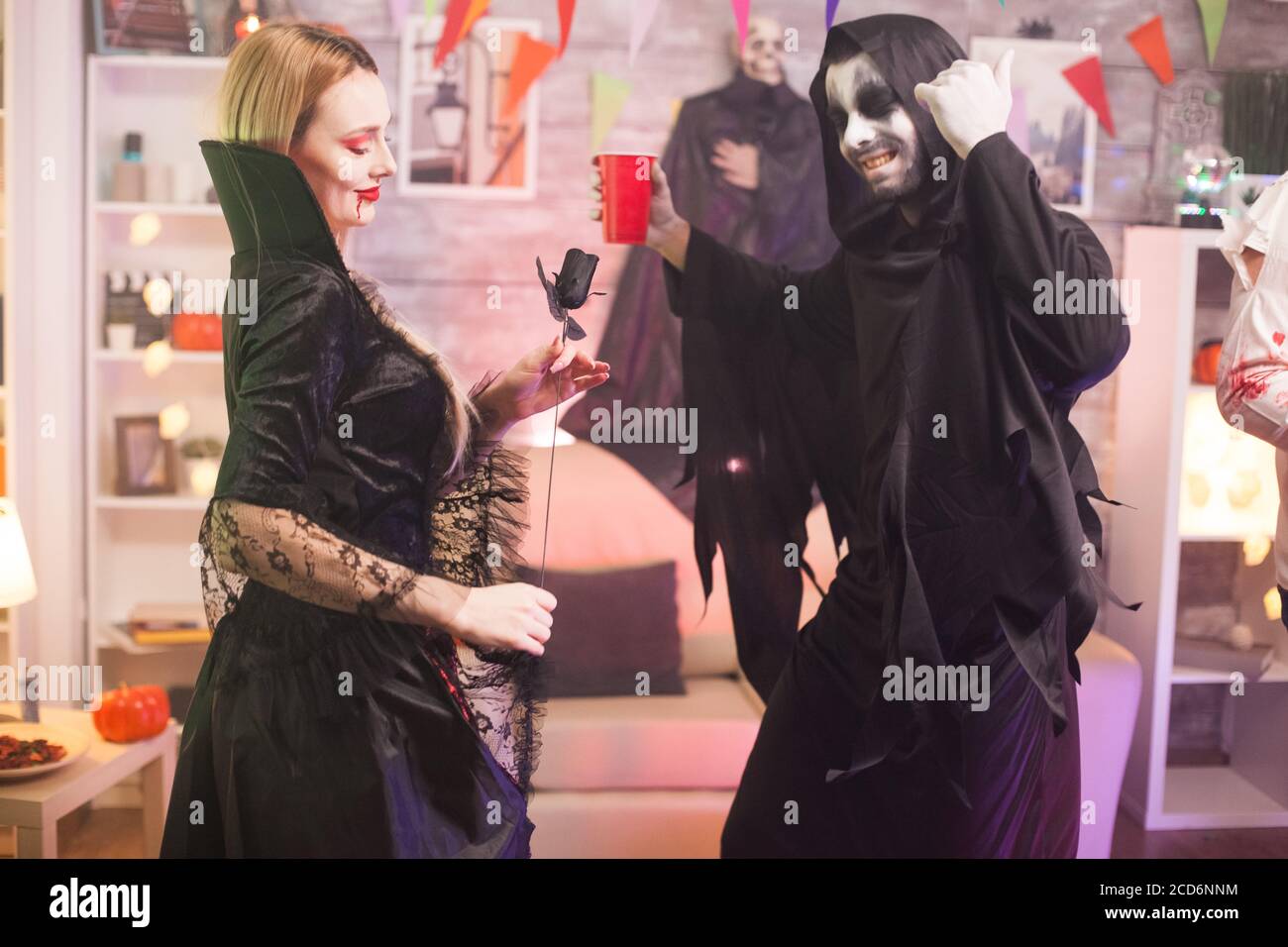 Grim reaper and beautiful vampire woman having fun at halloween party ...