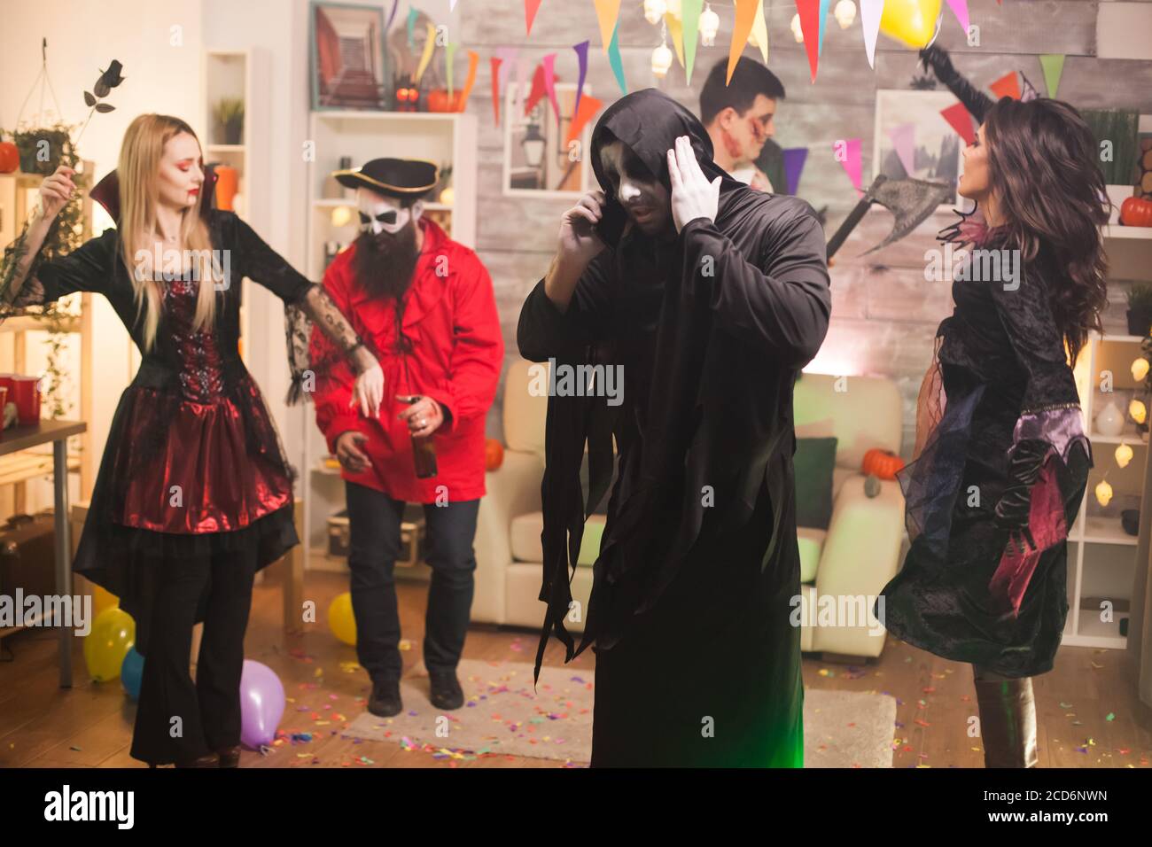 Grim reaper talking on the phone at halloween celebration. Loud music ...