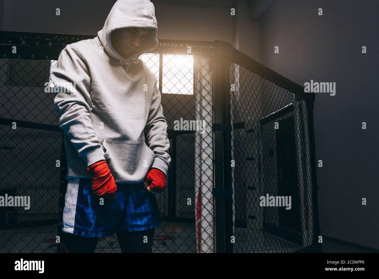 Boxer man in sportswear with hood on head posing in a dark studio ...