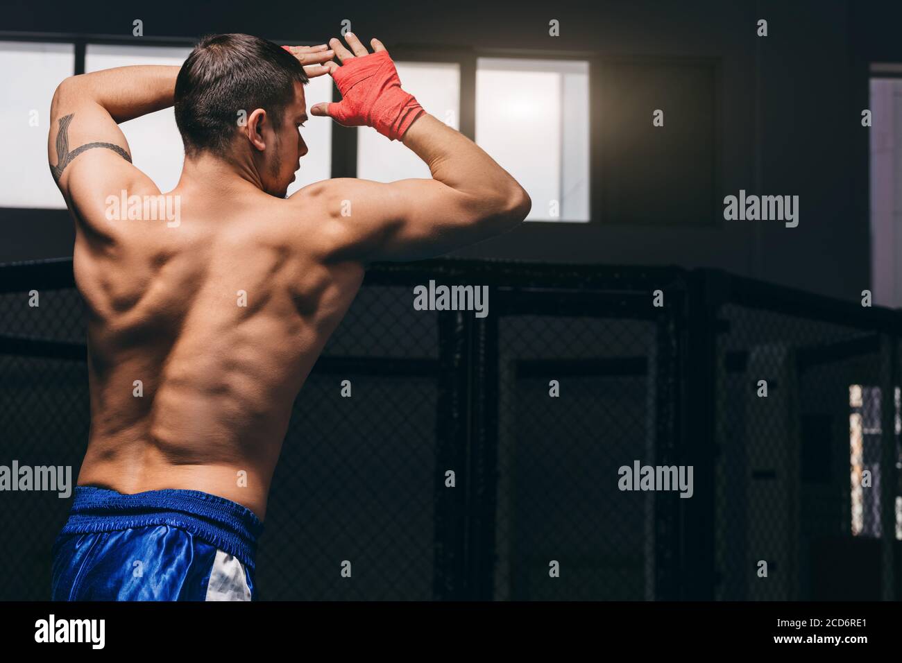 Strong muscular young boxer in sportswear training in dark studio ...