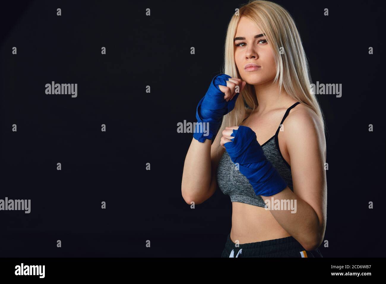 Attractive blonde woman fighter in boxing bandages posing in defense ...