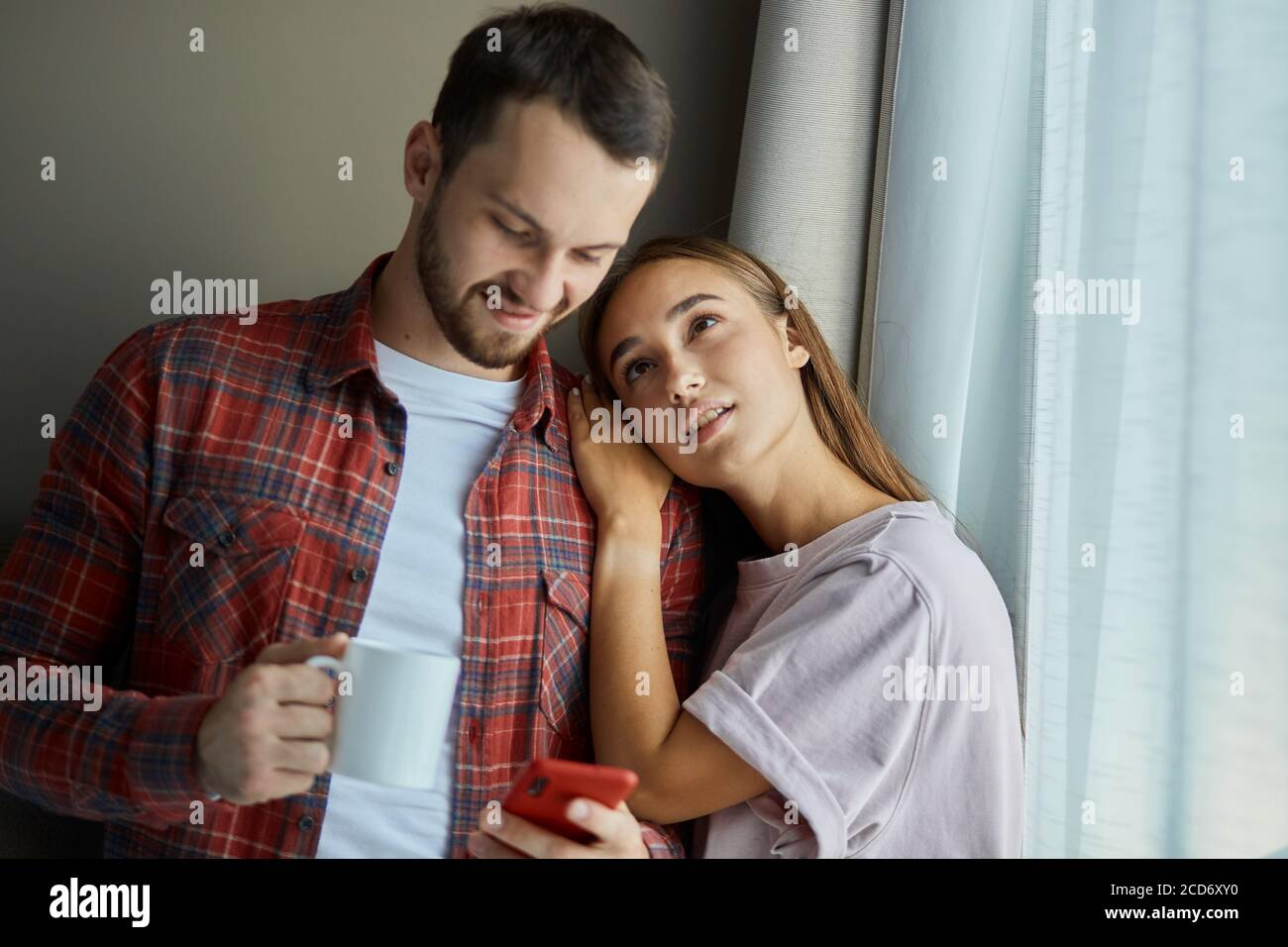 Romantic pretty girl looks up with admire, puts head on shoulder of ...
