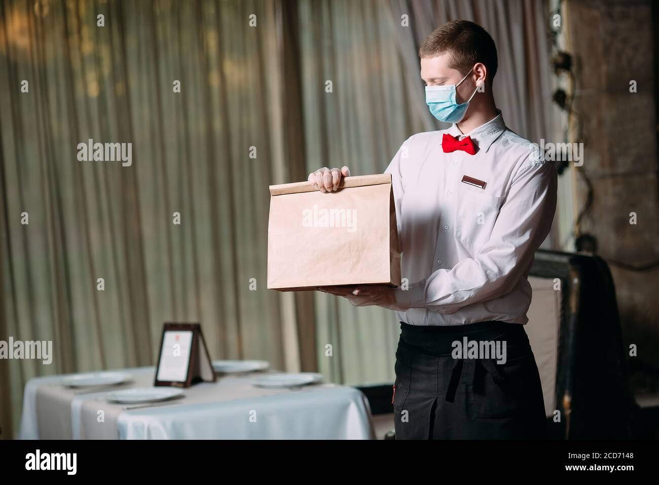 Food delivery from the restaurant. Portrait of a waiter holding a craft ...