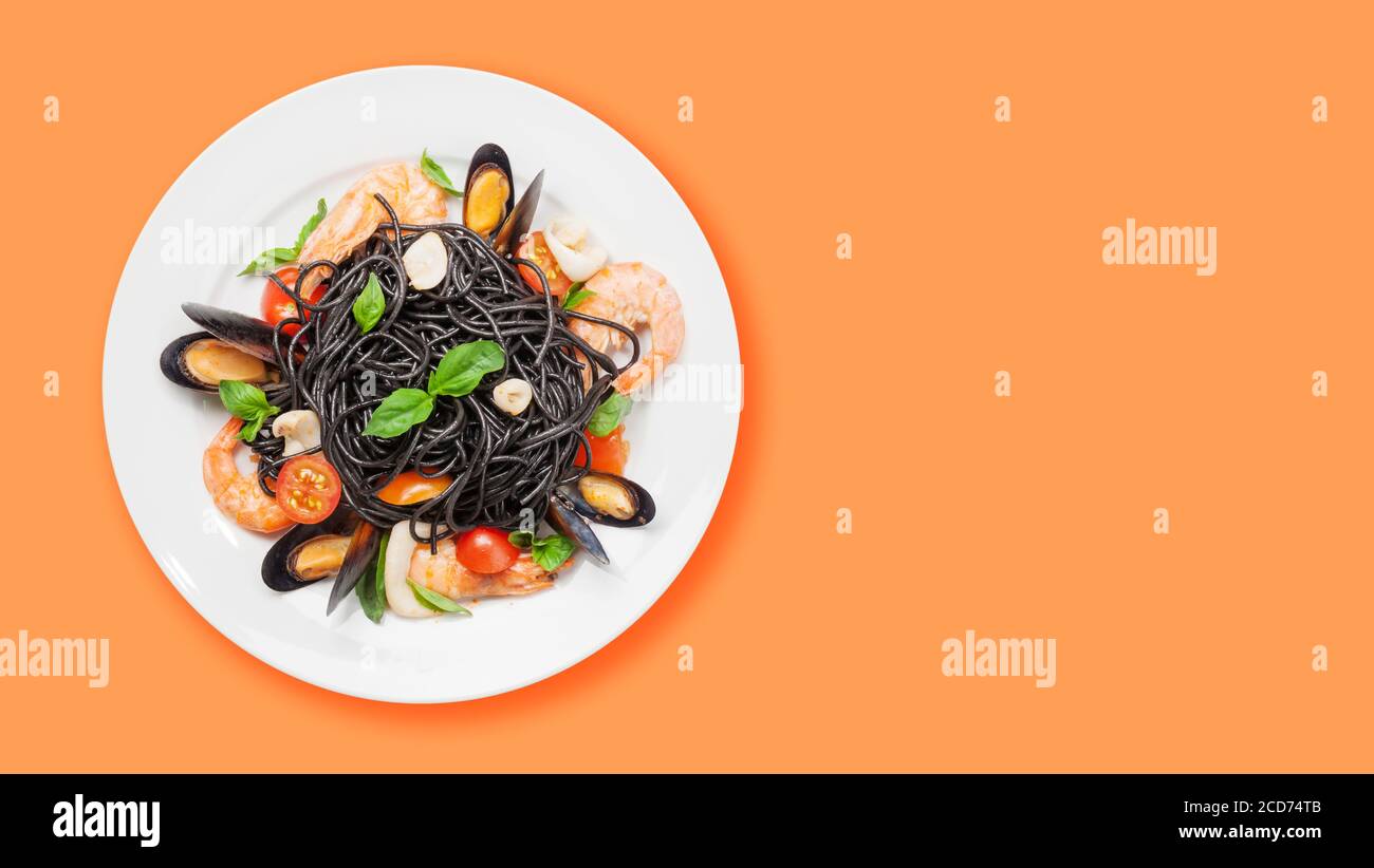 Black spaghetti pasta with seafood, tomatoes and basil. Top view flat ...