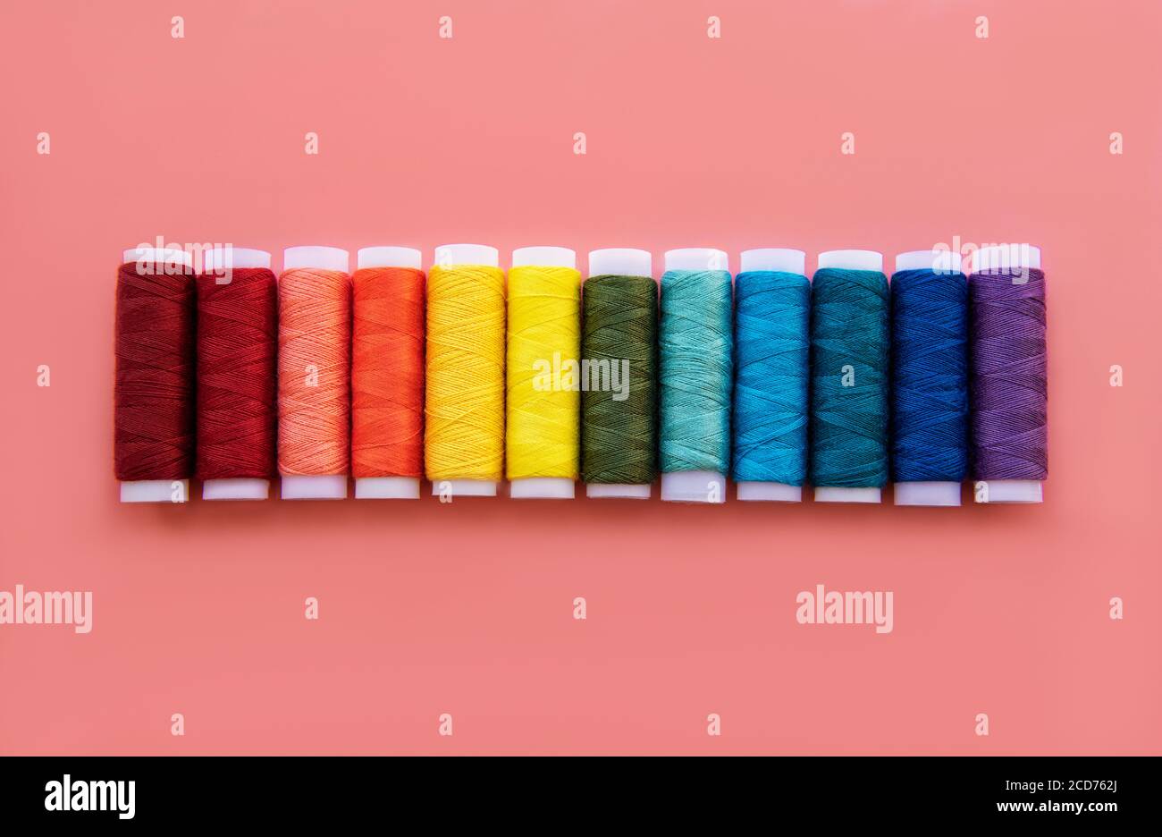 Spools of thread on the colors of the rainbow on a pink background ...
