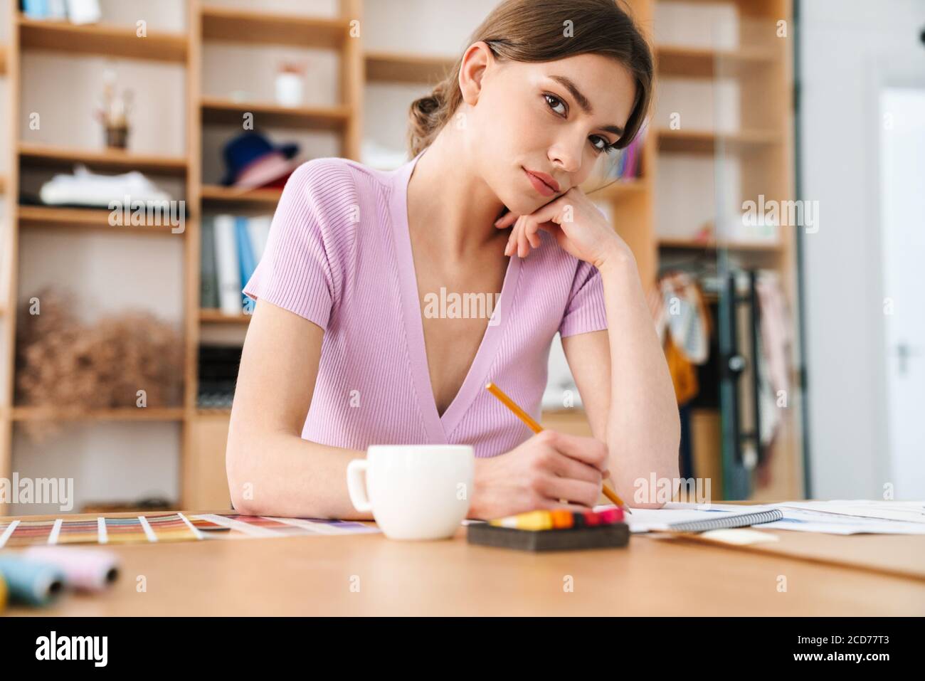 Image of a pretty serious young woman designer indoors at the table work with project Stock ...