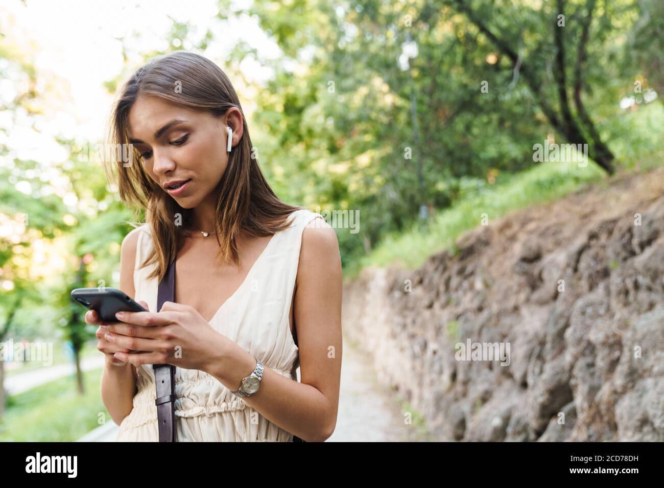 Image of young caucasian brunette woman wearing earbuds holding ...