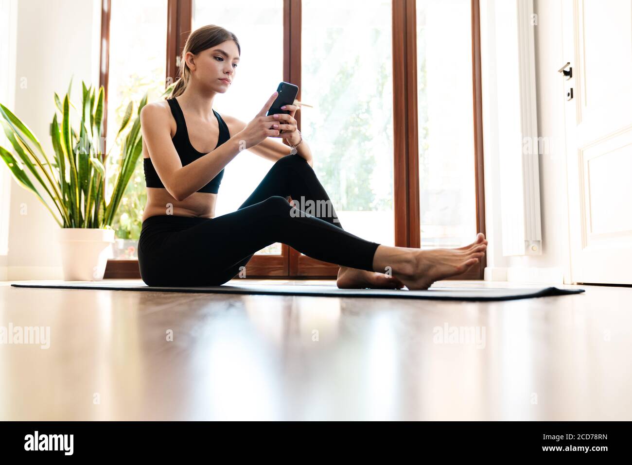 Fit young sports woman using cellphone while doing exercise on a ...