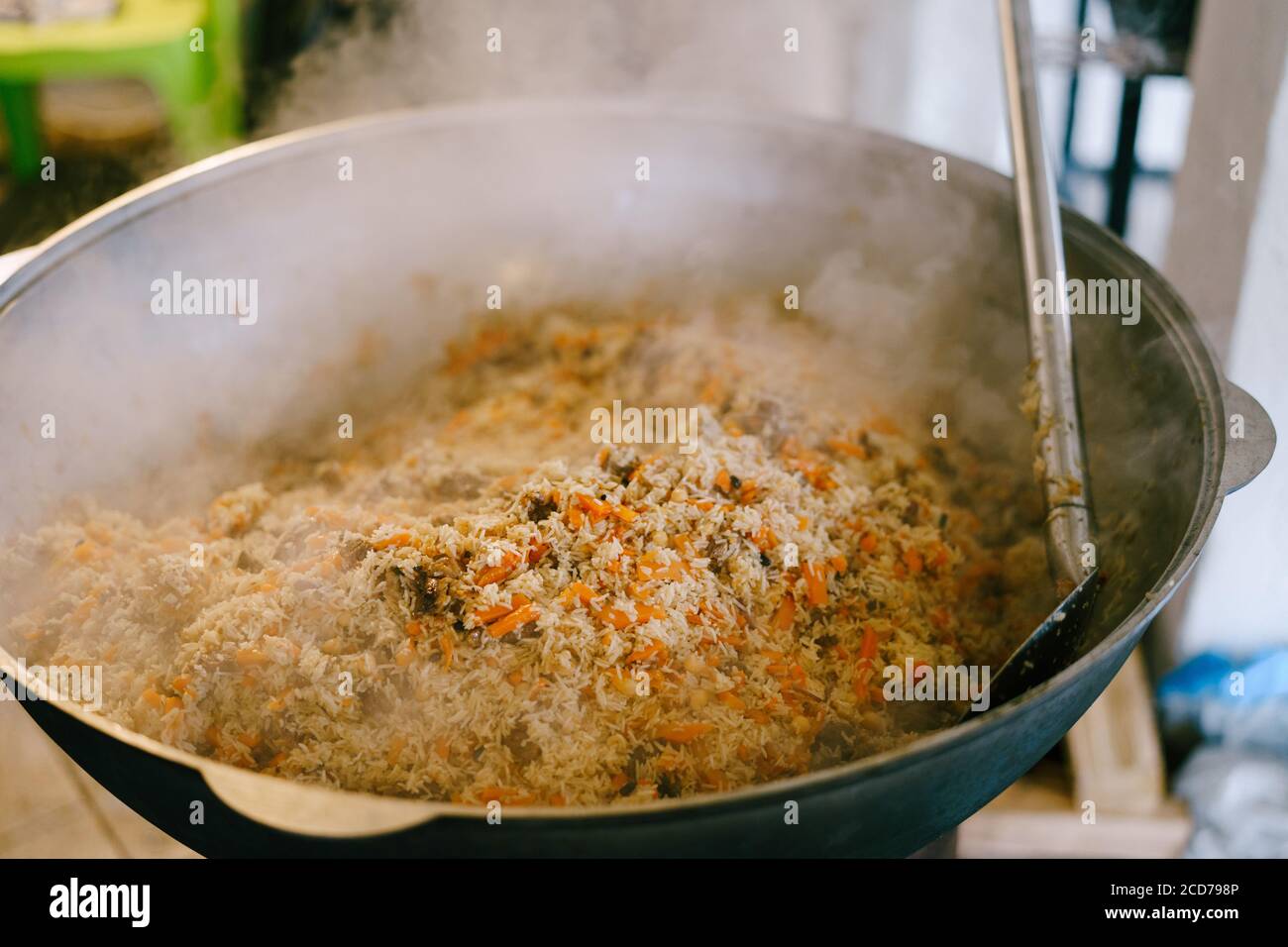 The cook stirs pilaf in the cauldron Stock Photo - Alamy