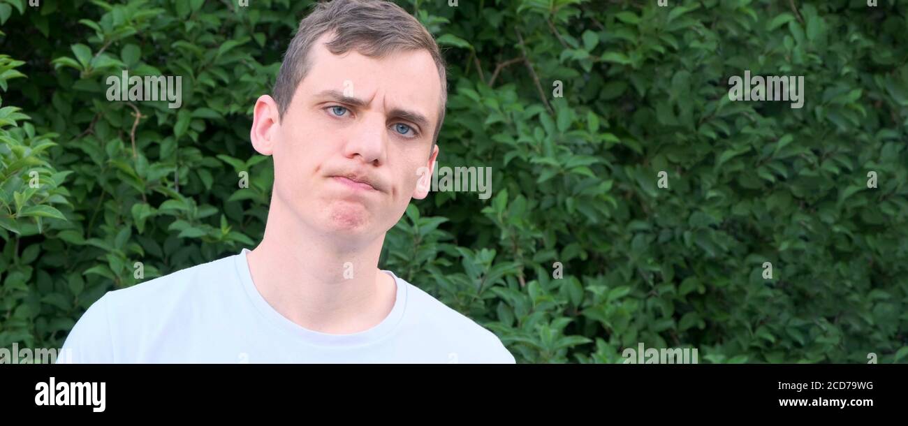 Portrait of a young disappointed man with blue eyes on a background of ...
