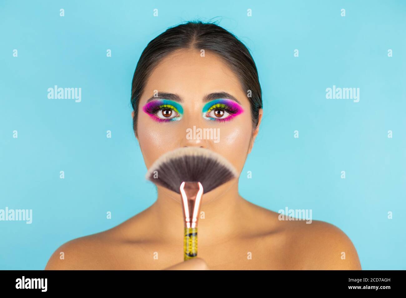 Beauty portrait of female model with vivid makeup and brush on blue ...