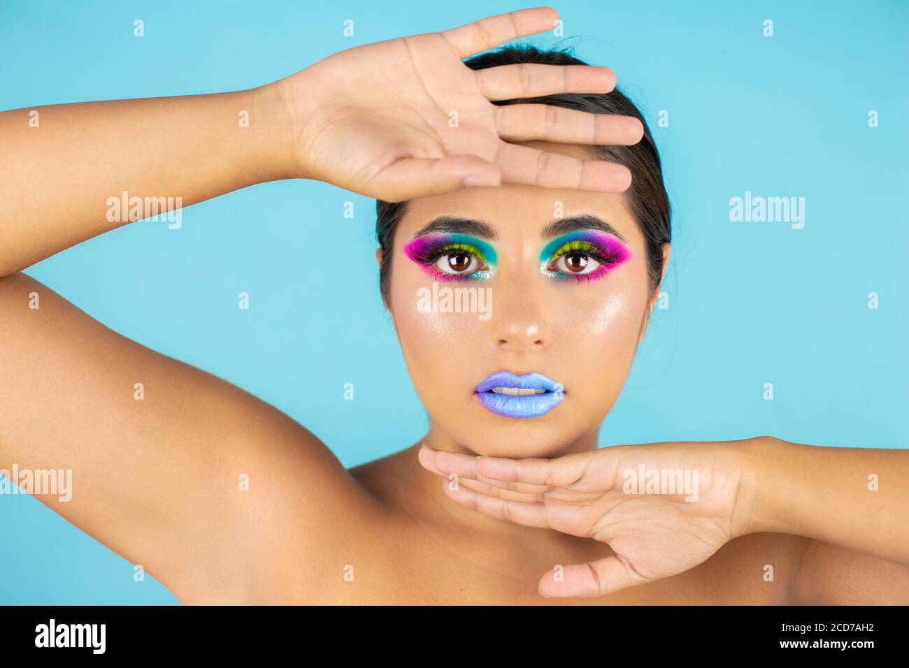 Beauty portrait of female model with vivid makeup on blue background ...