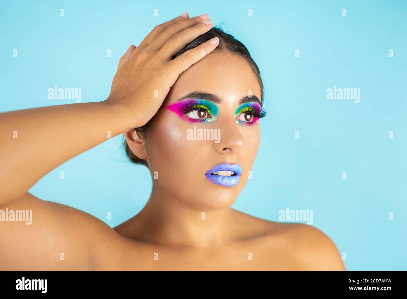 Beauty portrait of female model with vivid makeup on blue background ...