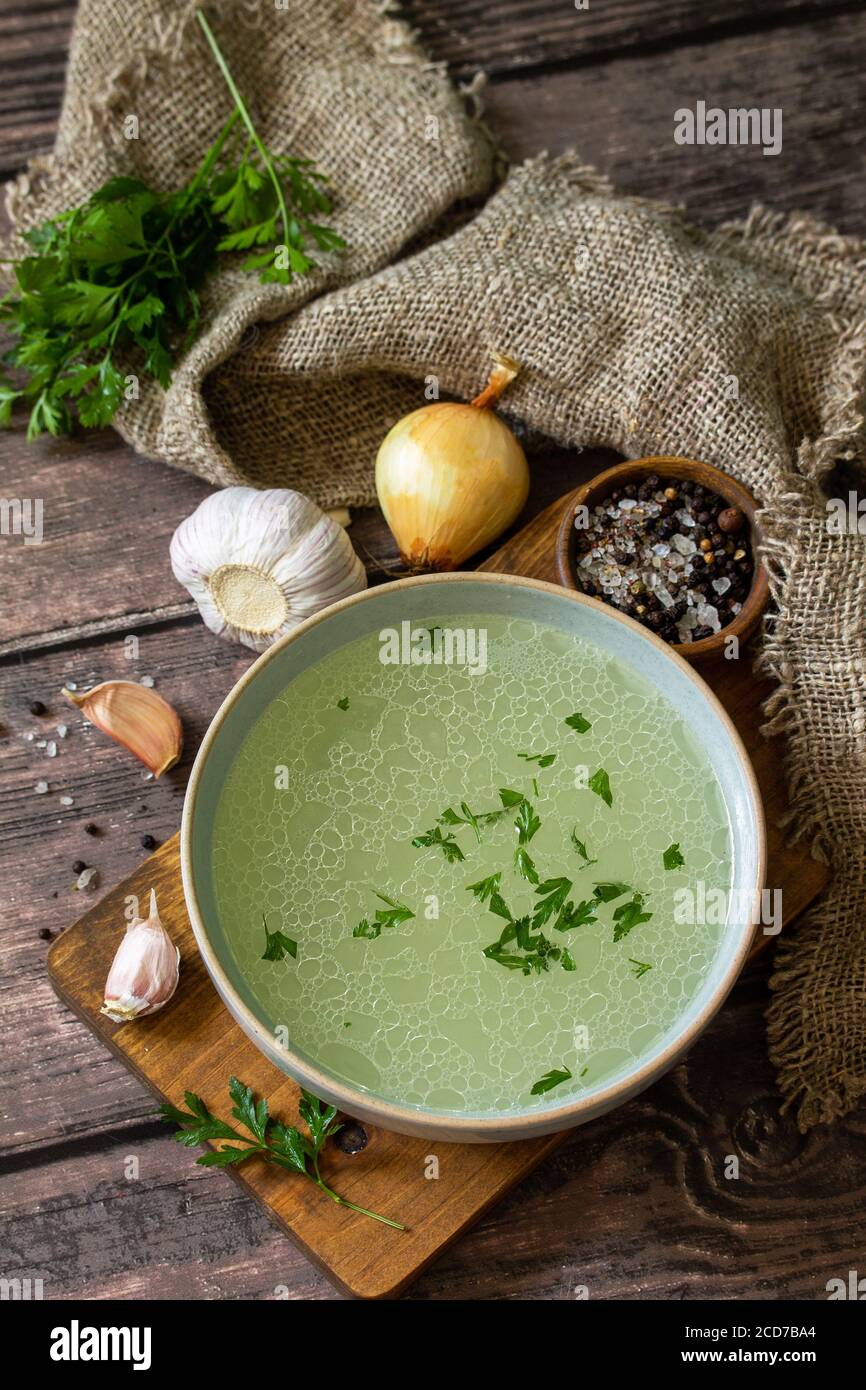 Hot rich meat broth (bouillon) with herbs on a rustic table Stock Photo ...