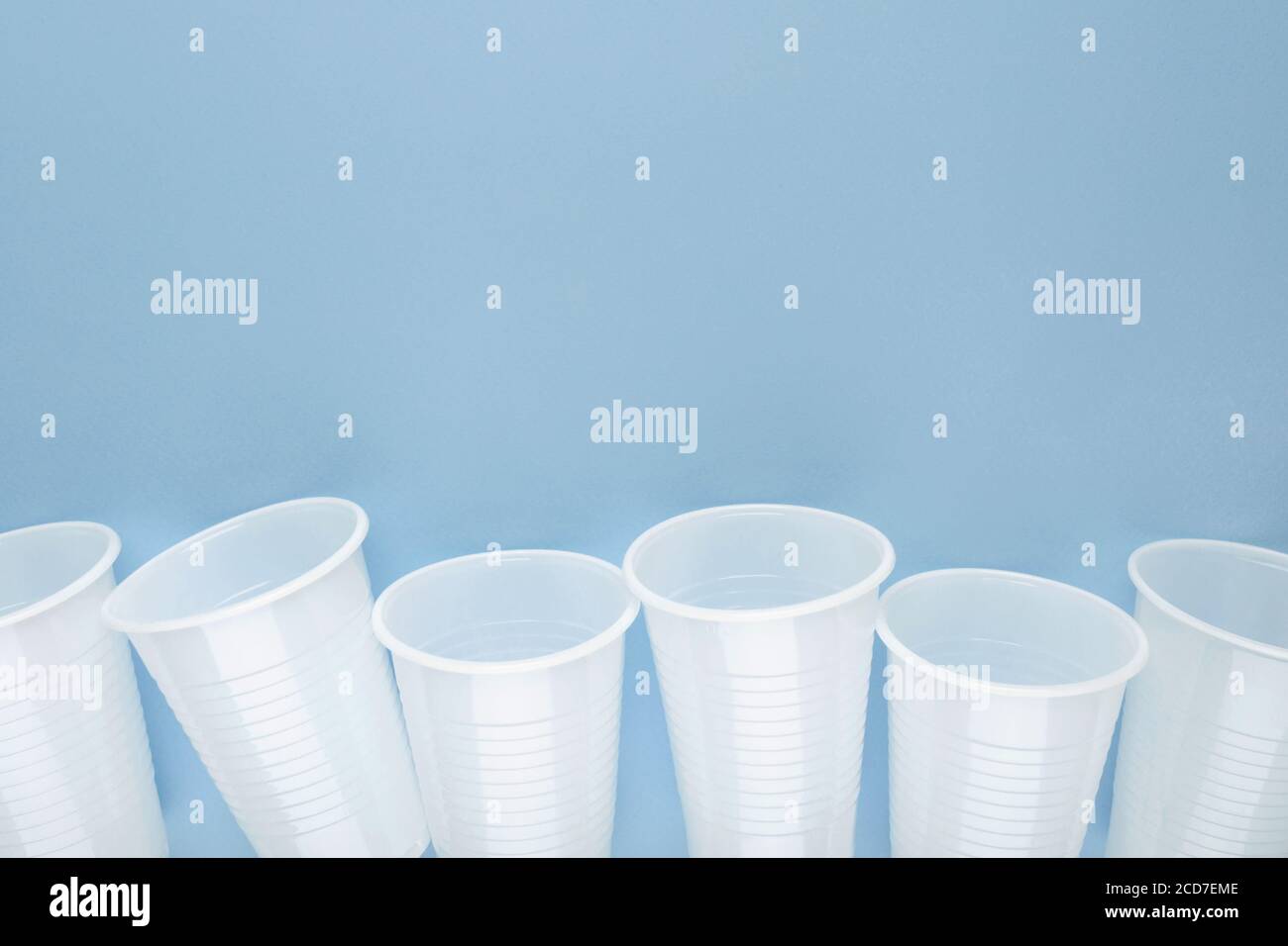 White plastic empty cups laid out in a row on blue background Stock ...