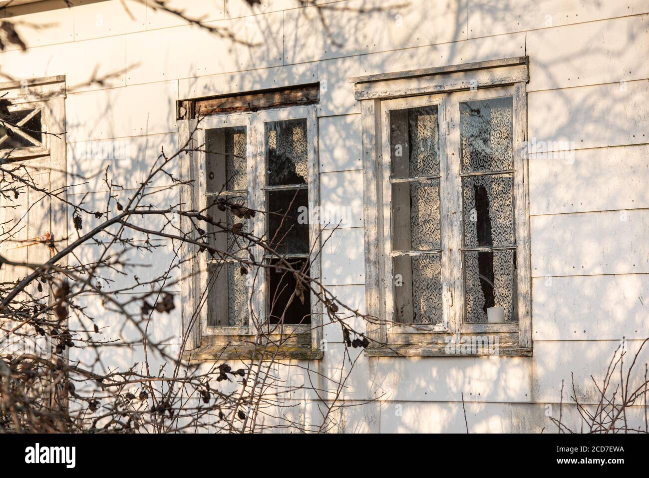 Broken windows of an old, abandoned house with asbestos wall tiles ...