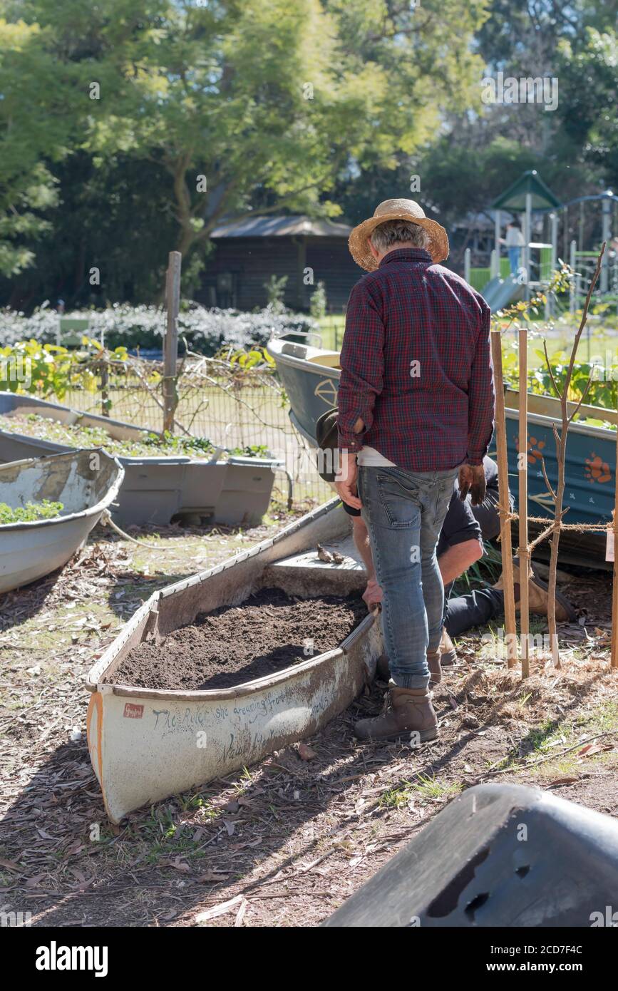 Volunteering locals prepare a new vegetable garden bed in a repurposed ...