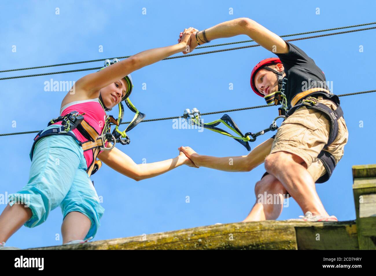 Partner exercise for teamwork in a high ropes course Stock Photo - Alamy