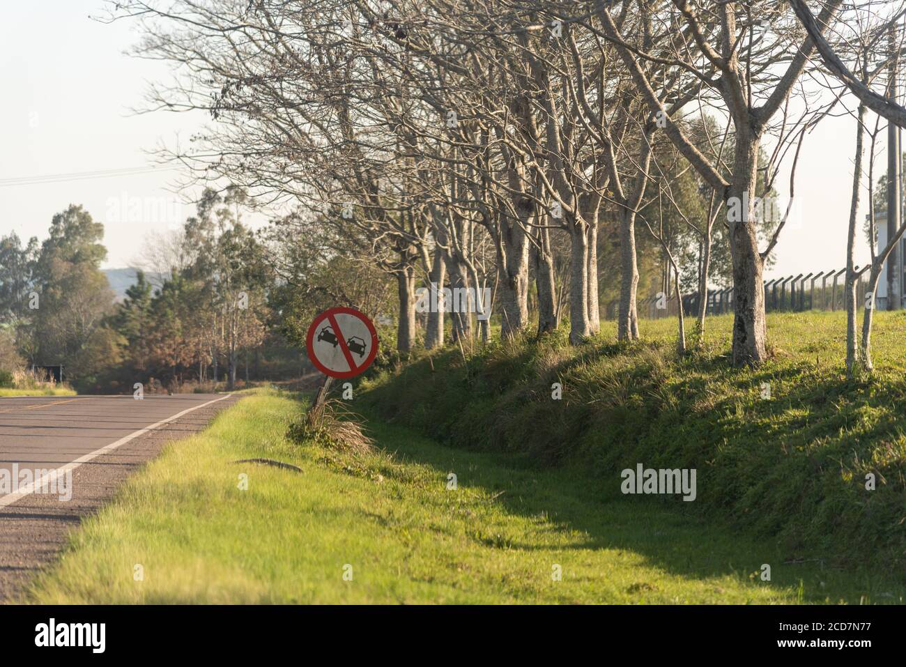 A highway and the "no overtaking" traffic sign are crooked beside the ...