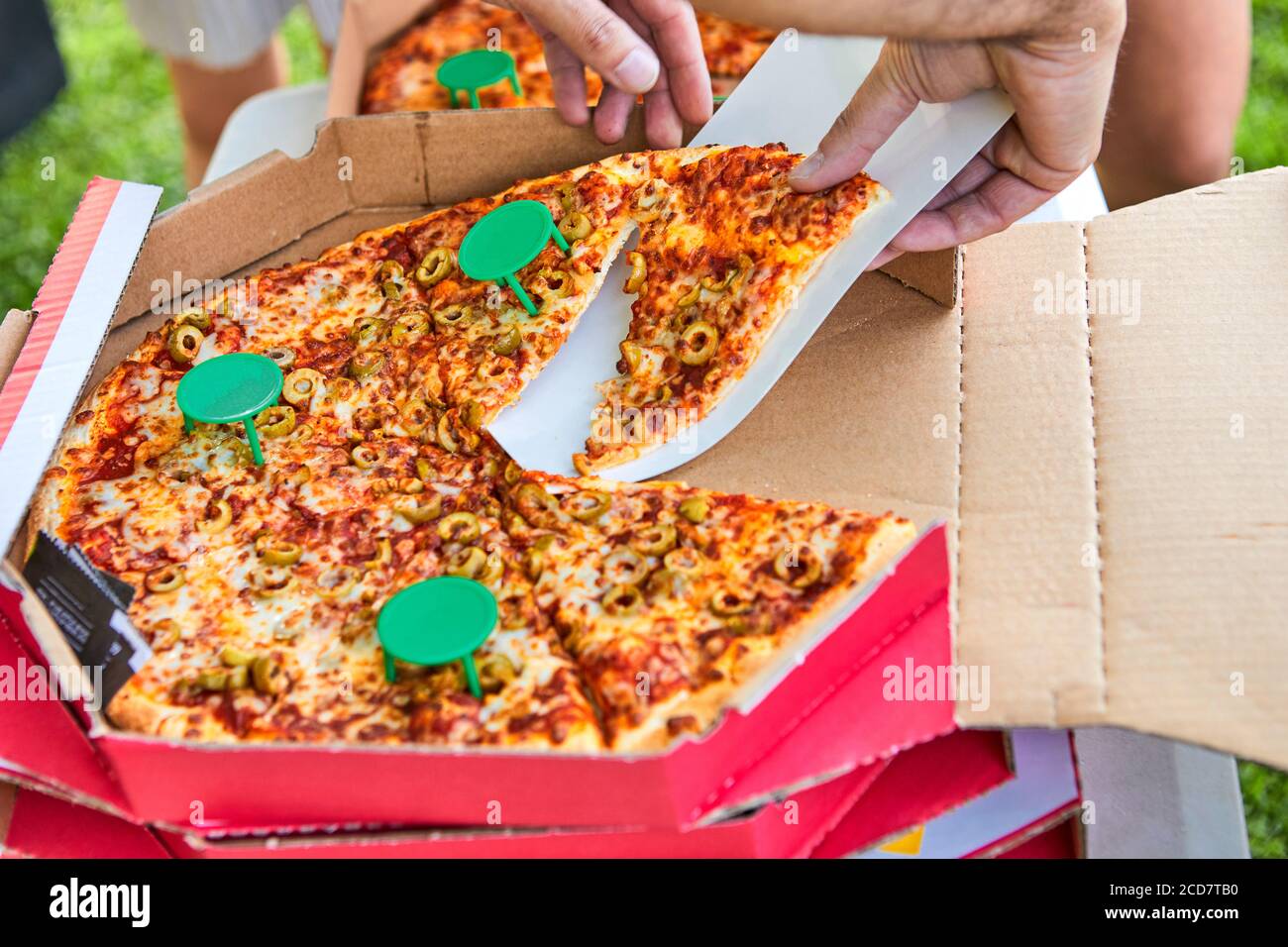 Man hand holding a slice of delicous pizza, eating pizza in a park ...