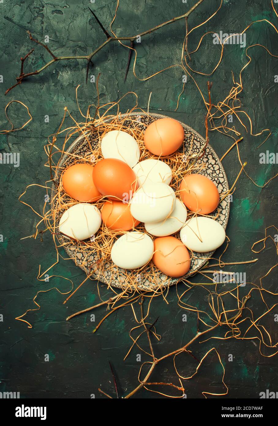 Multicolored chicken eggs with straw and branches, spring Easter ...