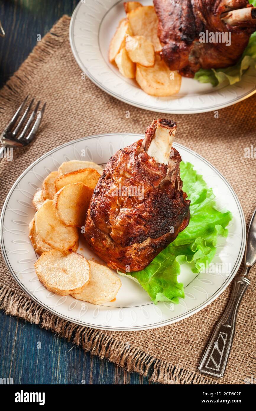 Roasted turkey knuckle with fried potato slices on a plate Stock Photo ...