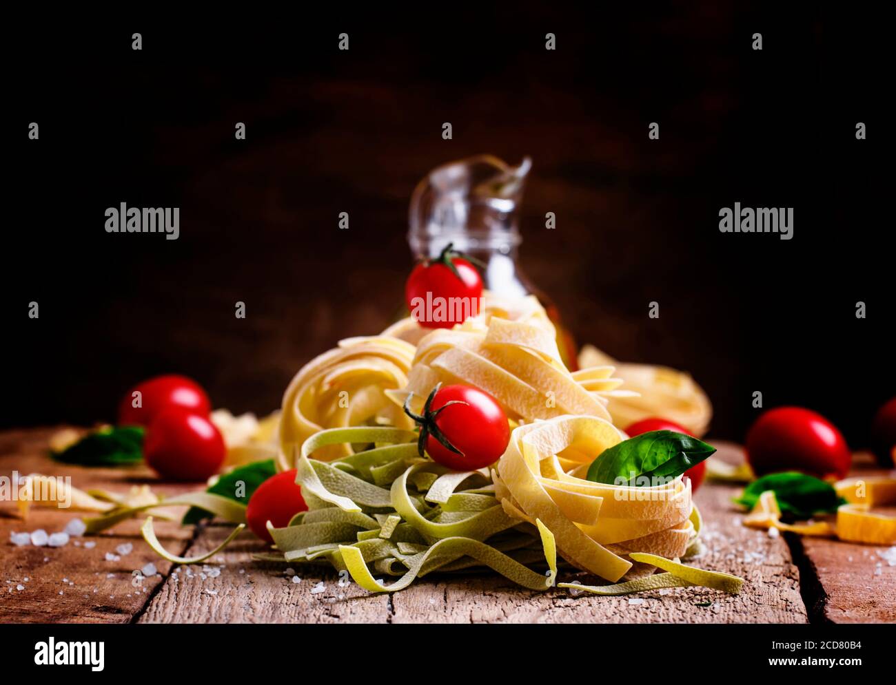 Still life in rustic style. Nest of pasta with cherry tomatoes, olive ...