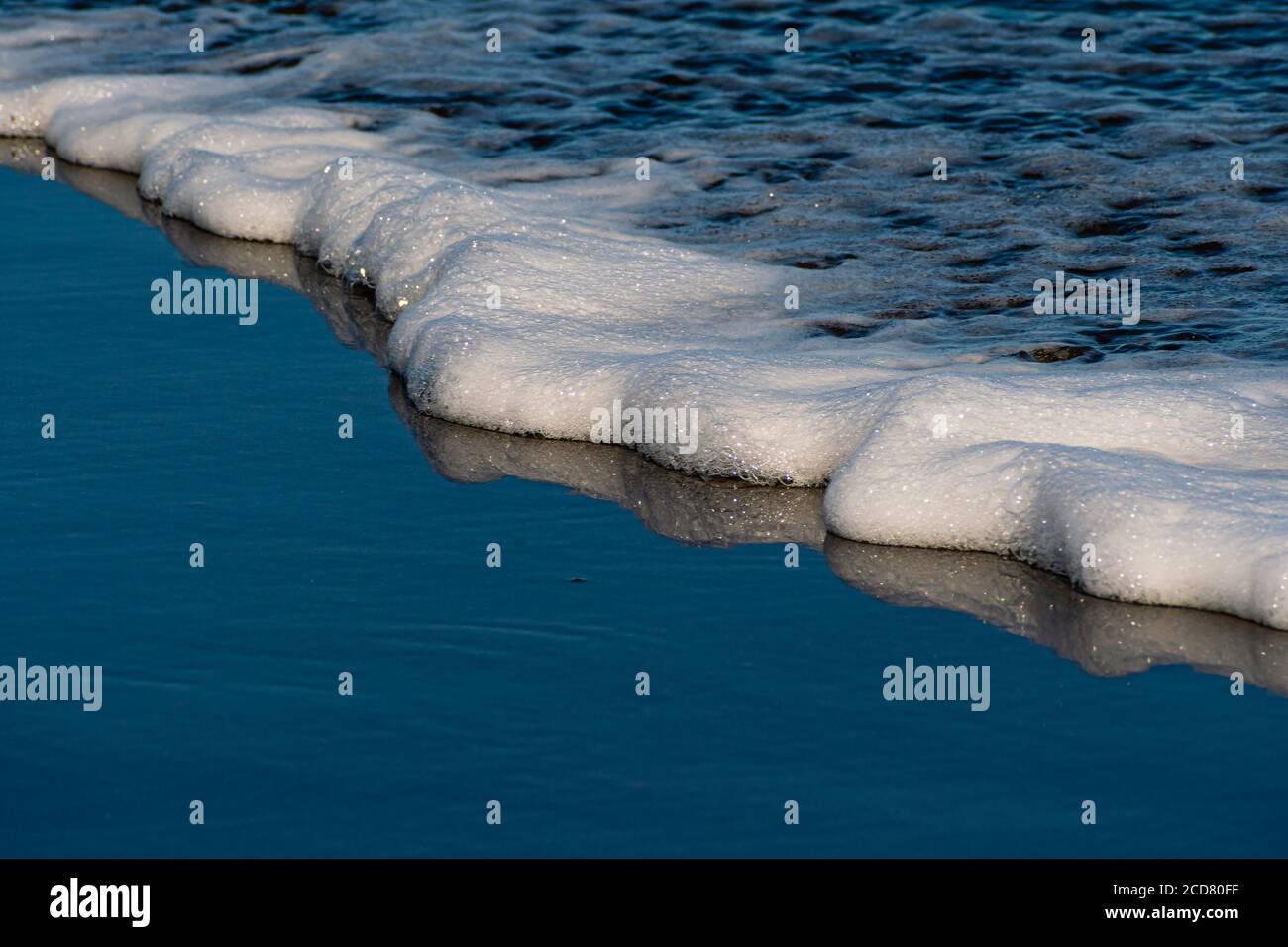 Seafoam of an ocean wave on sand beach Stock Photo - Alamy