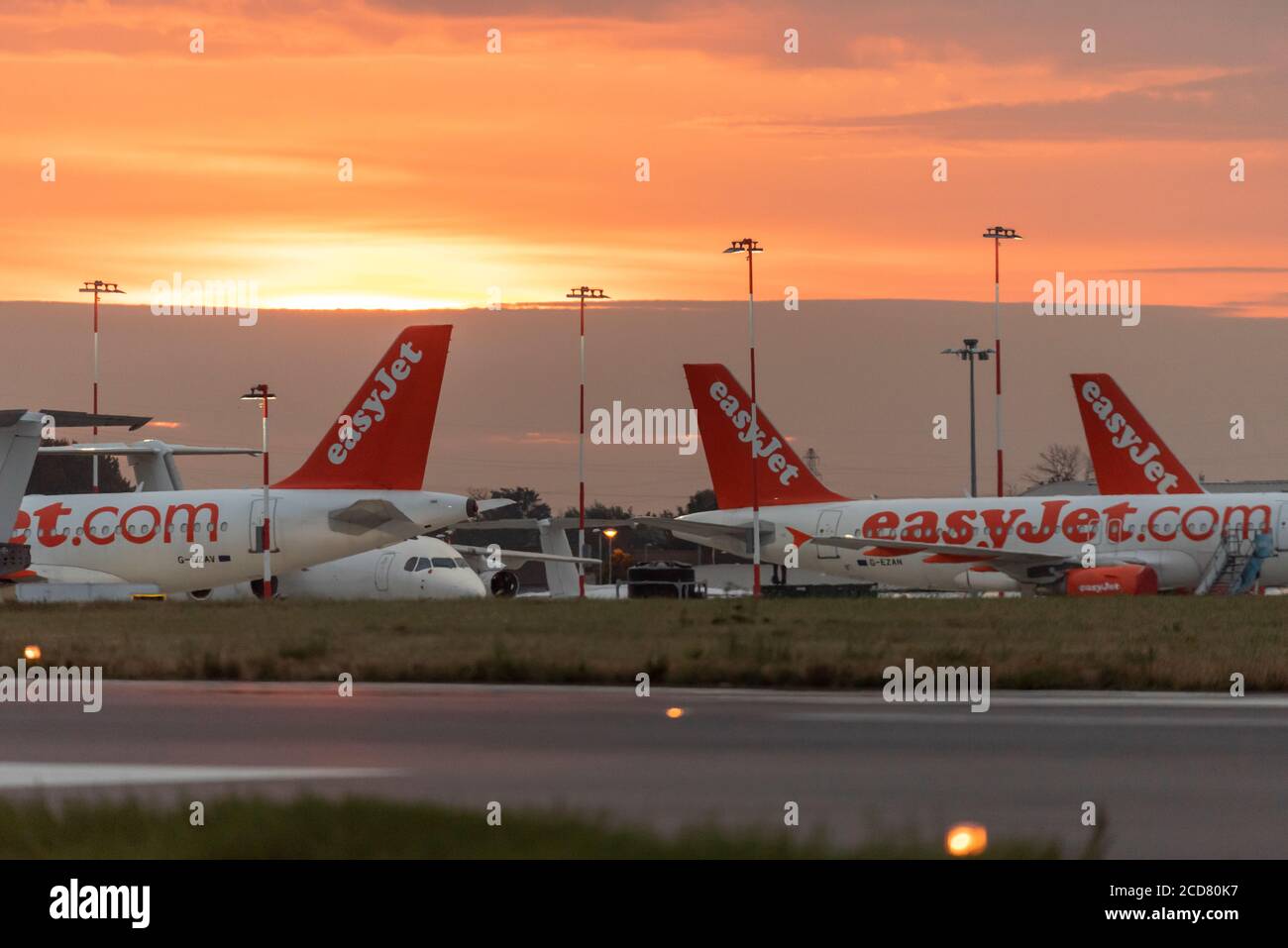 Red sky sunrise at dawn over stored easyJet planes grounded in storage ...