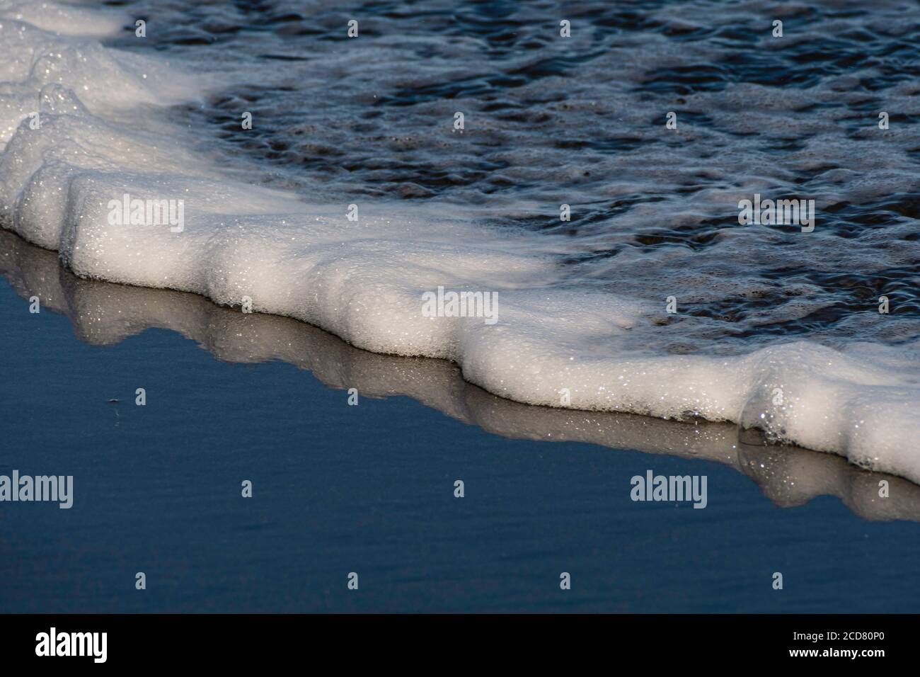 Seafoam of an ocean wave on sand beach Stock Photo - Alamy
