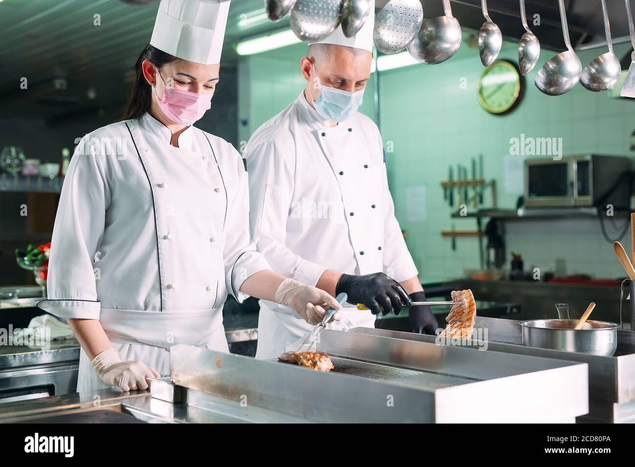 Cooks roast meat on the stove in the kitchen of a restaurant or hotel ...