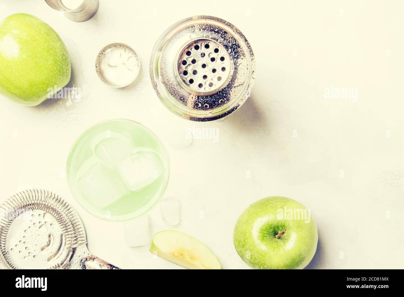 Summer alcoholic cocktail with green apple, vermouth and ice, bar tools ...