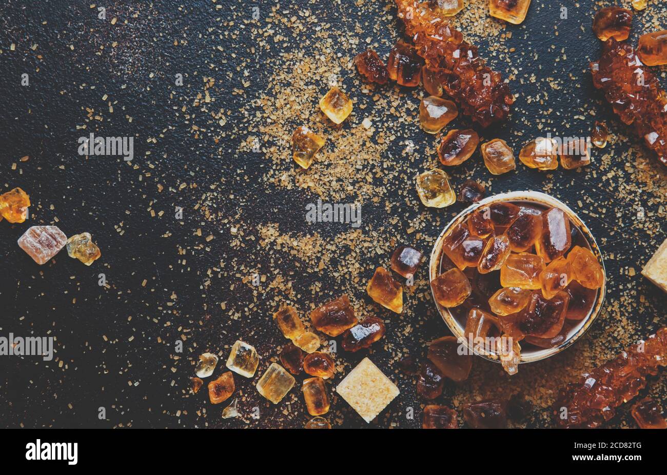 Sweet food background, assorted white and brown sugar on a dark ...