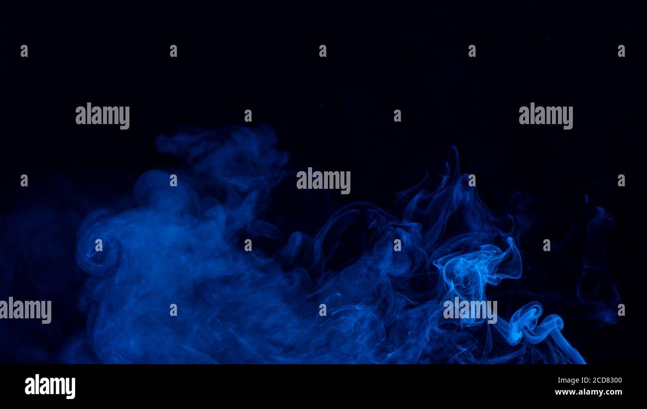 Conceptual image of blue color smoke isolated on dark black background ...