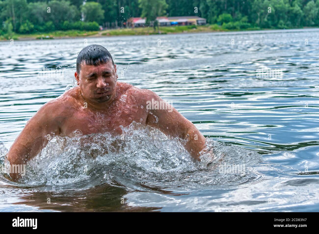 A man emerges from under the water, swimming in a cool river in summer ...
