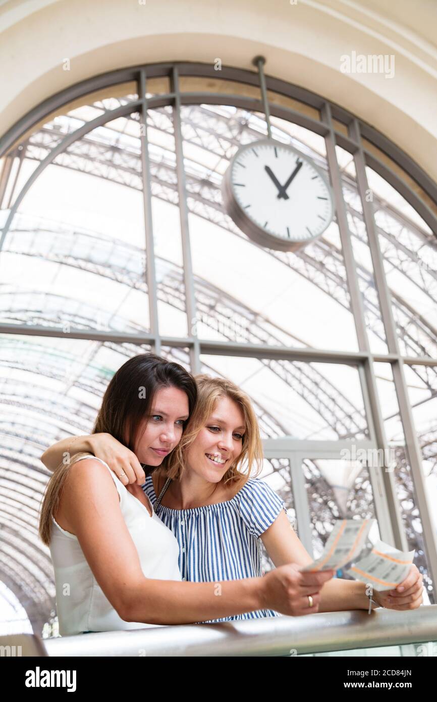 Girls in waiting room looking at train tickets Stock Photo - Alamy