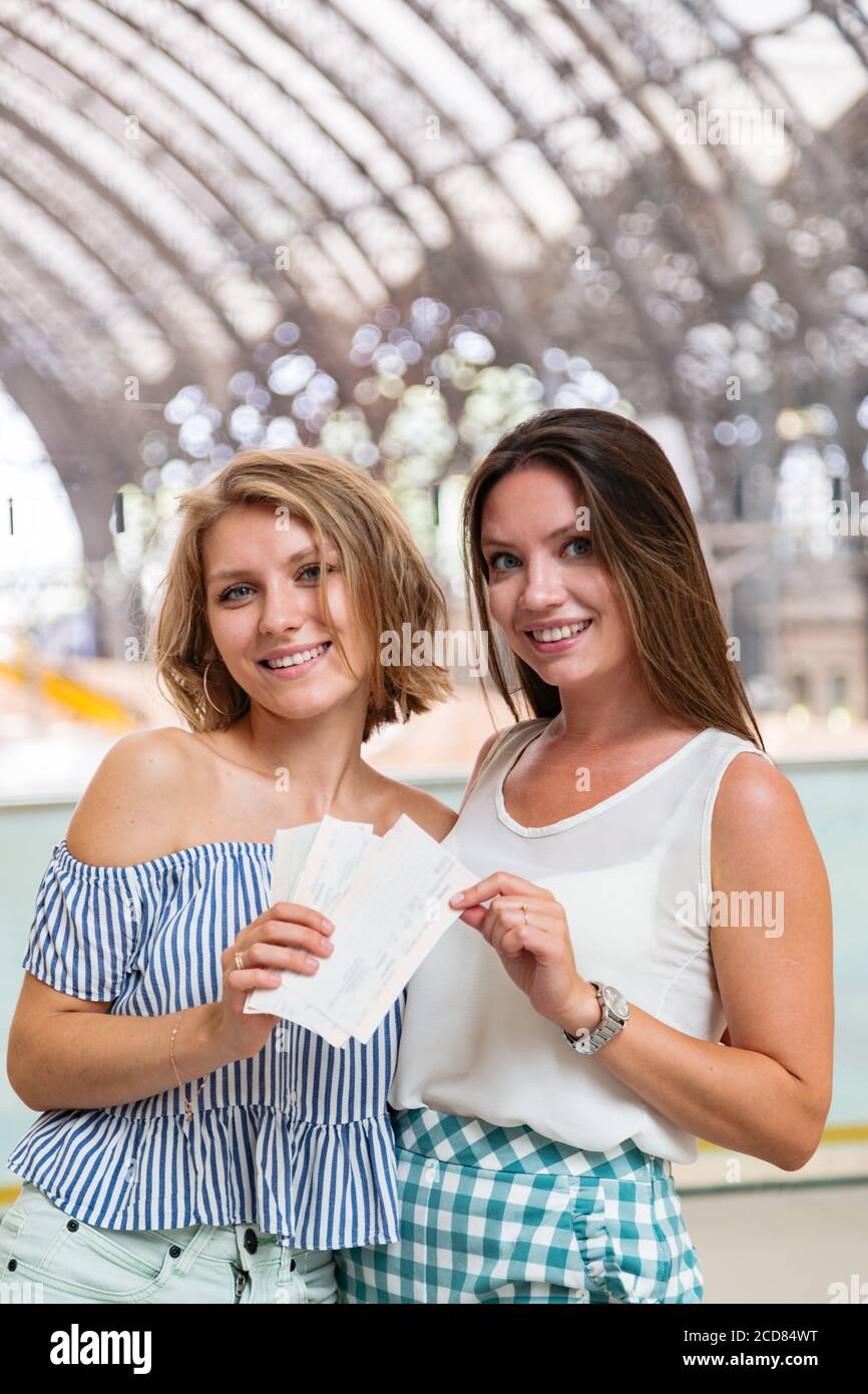 Two happy girls hugging and holding train tickets Stock Photo - Alamy