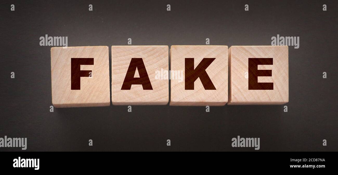 FAKE word written in wooden blocks on black Stock Photo - Alamy