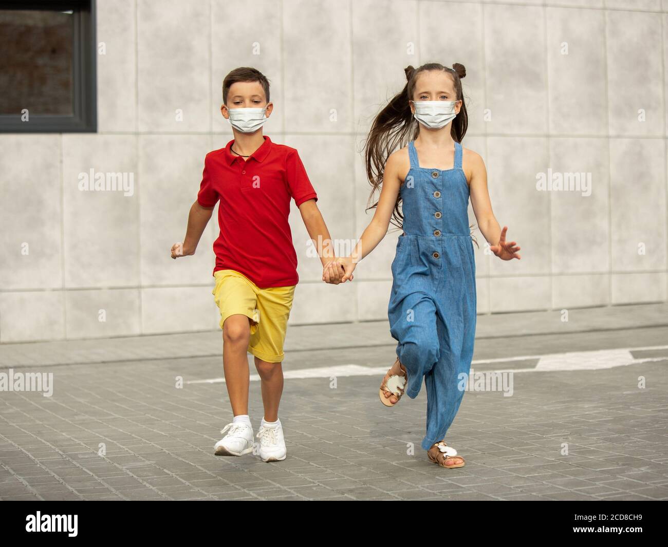 Happy little kids wearing protective face mask jumping and running on ...