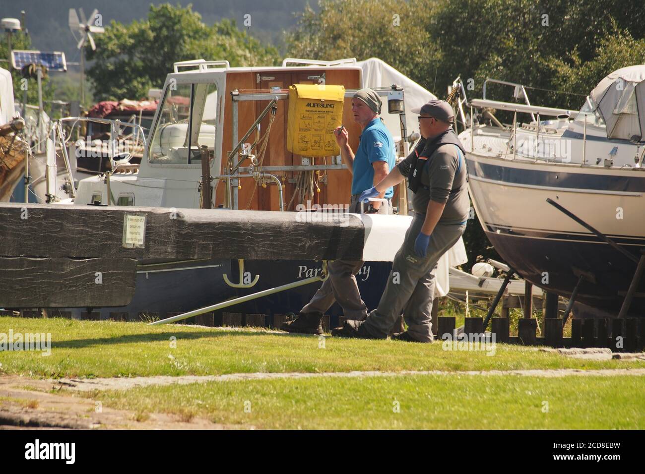 Two men both helping to open the lock gate by pushing the balance beam ...