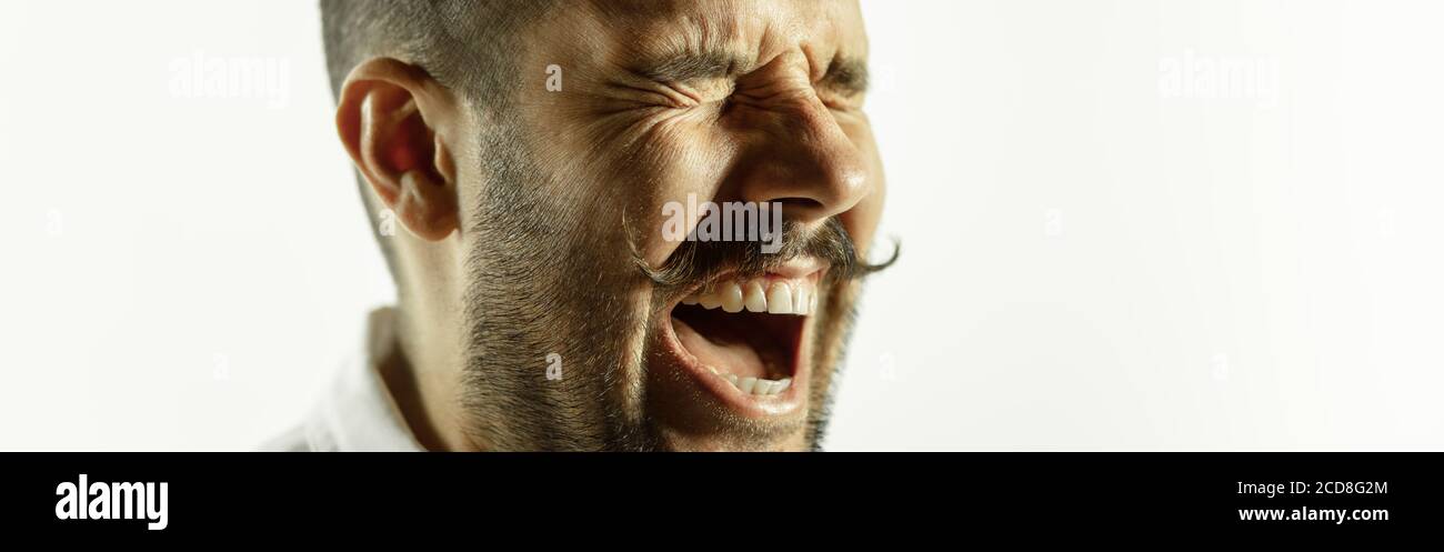 Screaming loud. Caucasian young man's close up cropped shot on studio ...