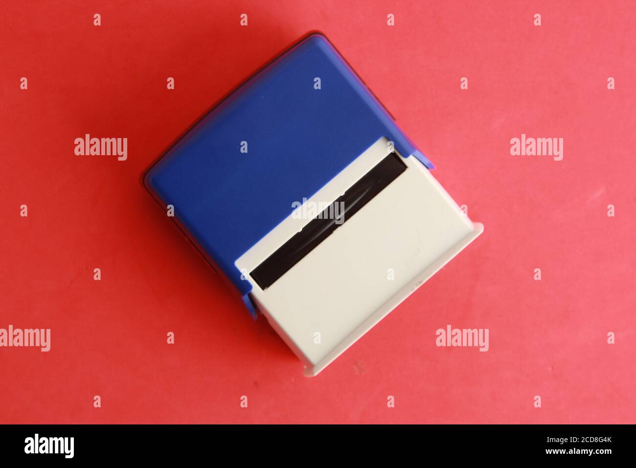 Automatic ink stamp on a red surface Stock Photo - Alamy