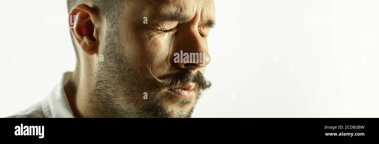 Crying. Caucasian young man's close up cropped shot on studio ...