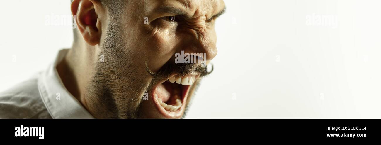 Angry scream. Caucasian young man's close up cropped shot on studio ...